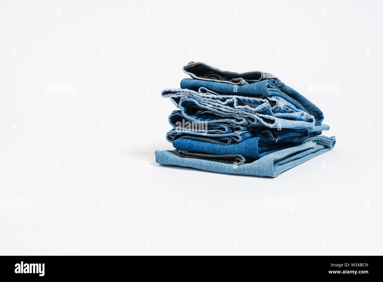 Stack of different blue shade jeans on white background. Denim with ...