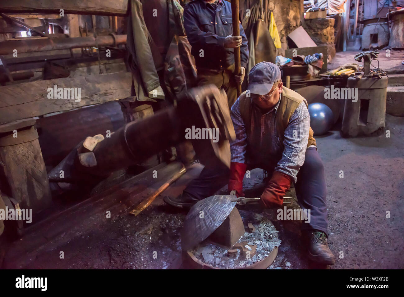 two real brutal traditional blacksmith workers working together with a ...