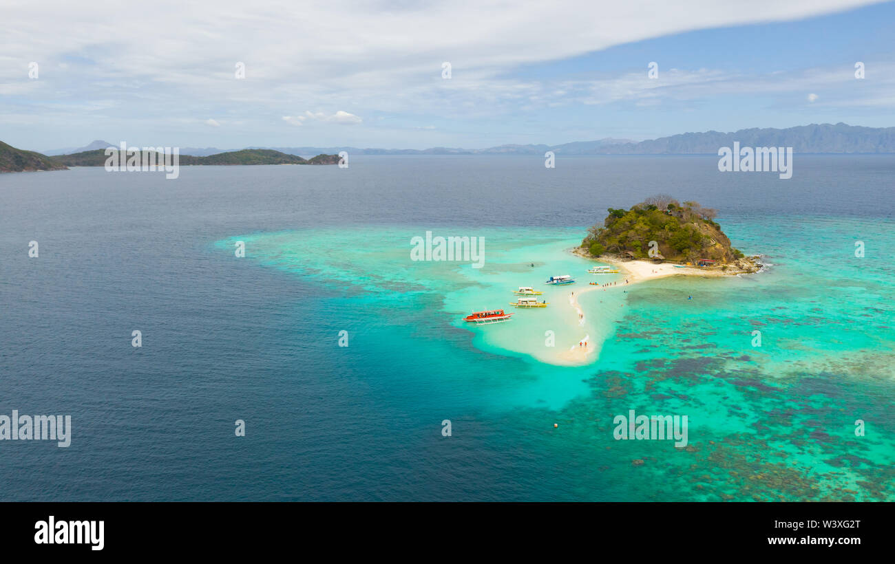 Island with a sand spit and coral reefs. Clear transparent sea near the ...
