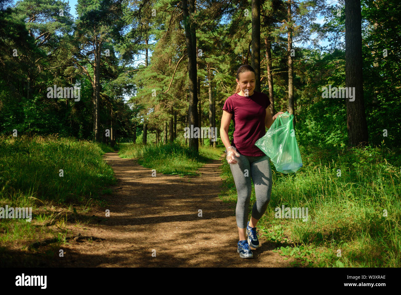 Woman collecting garbage in forest. At jogging or running. Plogging ...