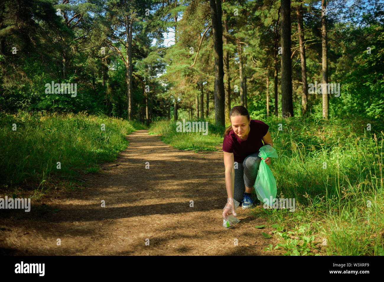 Woman collecting garbage in forest. At jogging or running. Plogging ...