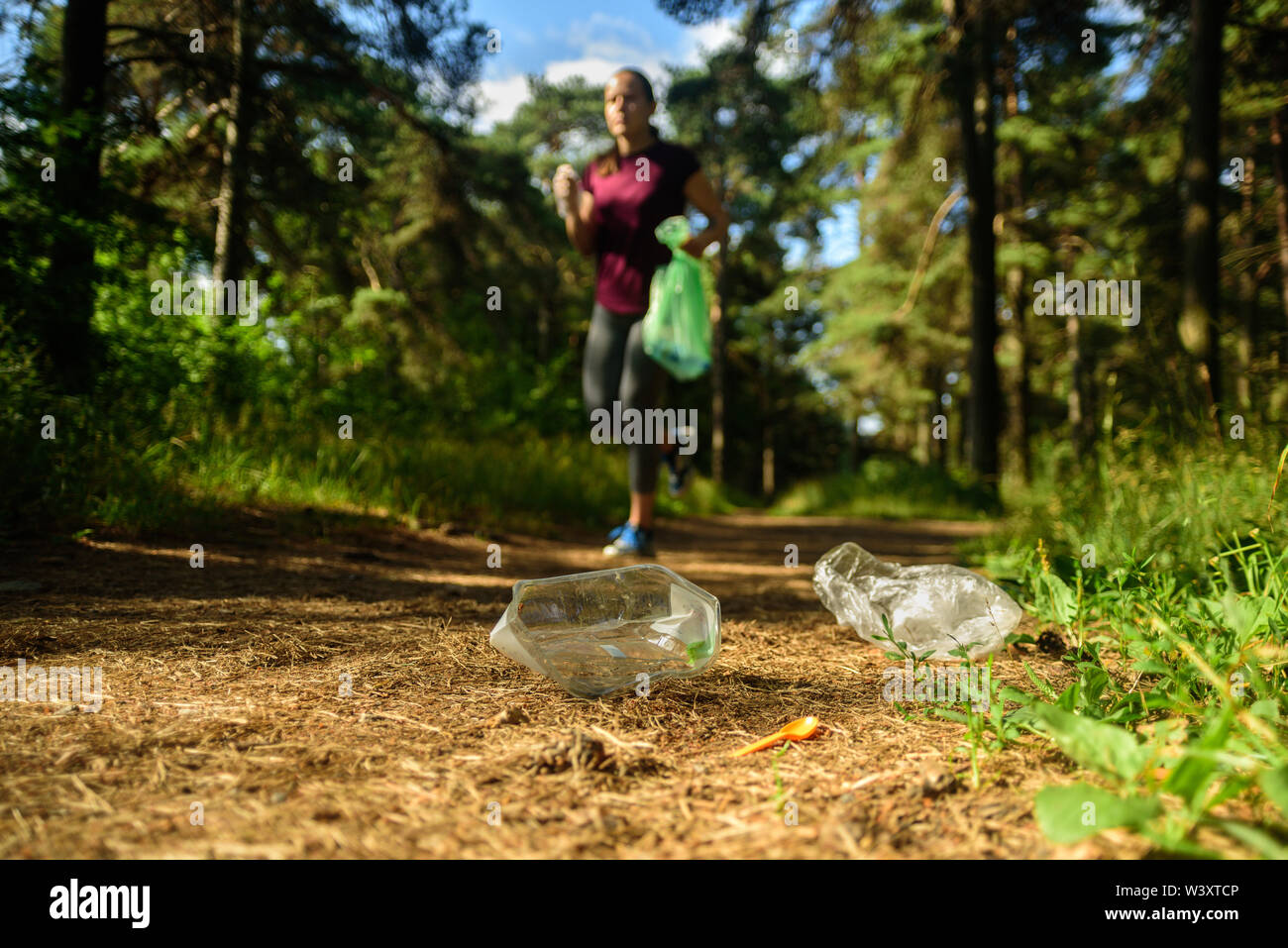 Woman jogging with garbage bag in forest. Collecting trash. Plogging ...