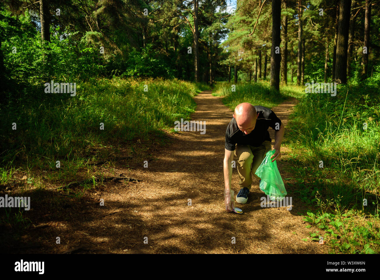 Man collecting garbage in forest. At jogging or running. Plogging ...