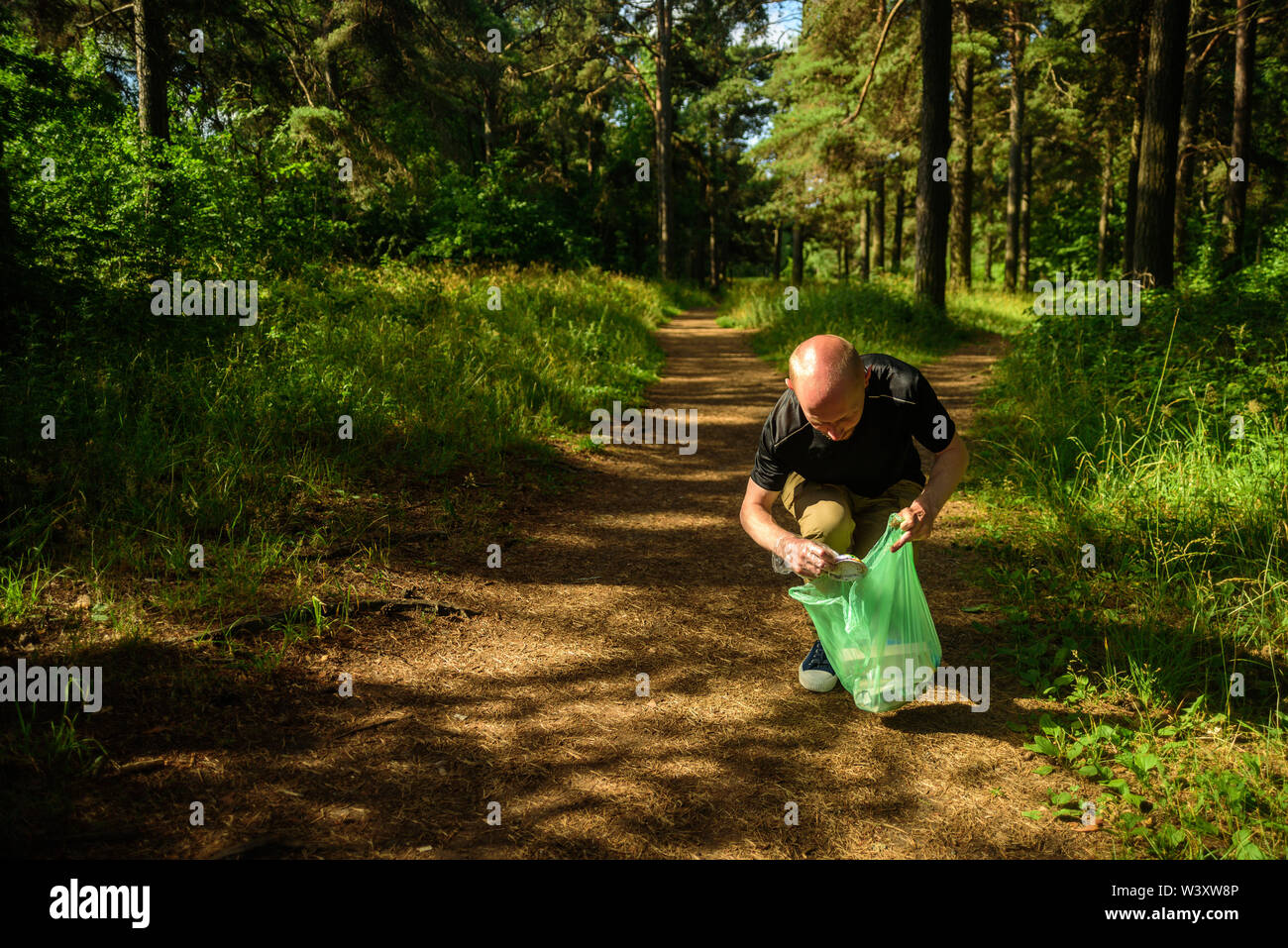 Man collecting garbage in forest. At jogging or running. Plogging concept Stock Photo - Alamy