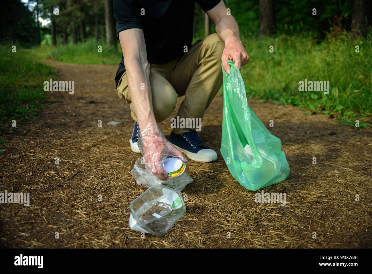 Man collecting garbage in forest. At jogging or running. Plogging ...