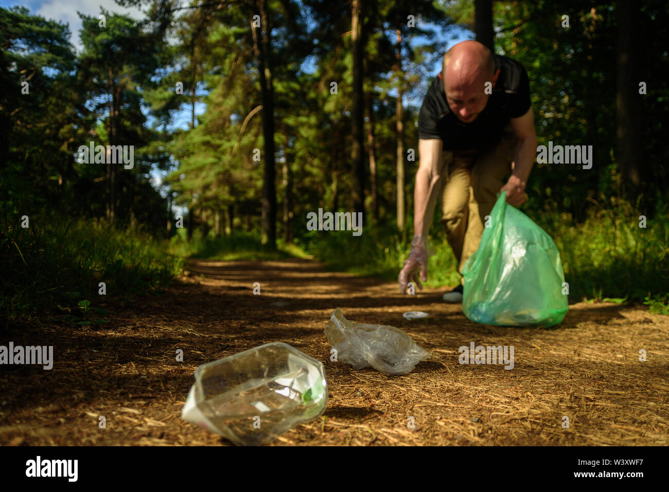 Man collecting garbage in forest. At jogging or running. Plogging ...