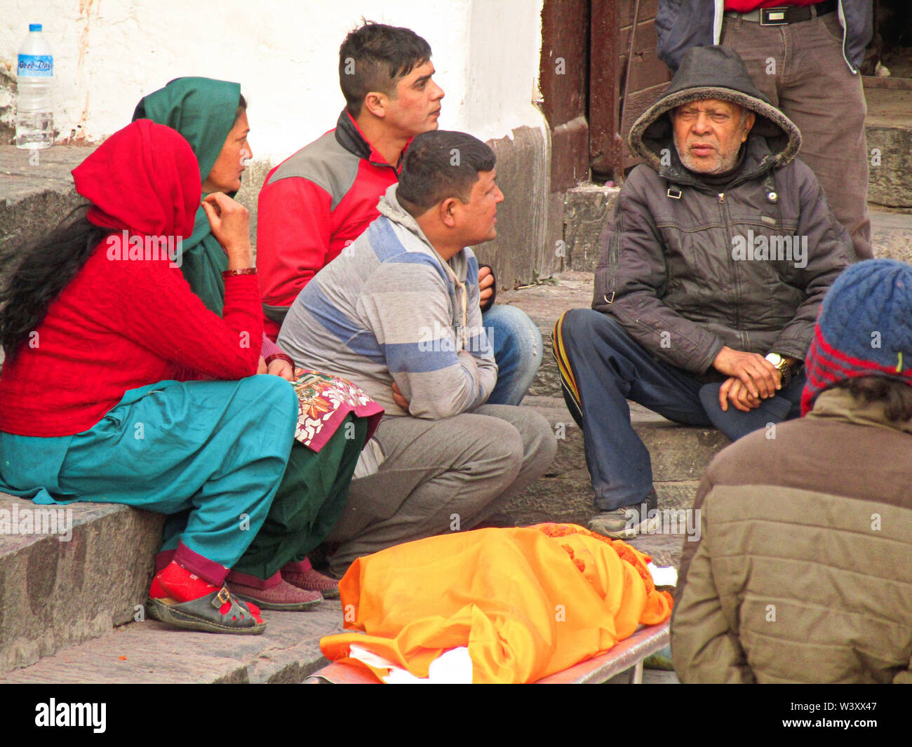 A group of Asian people sitting around waiting to cremate a dead body ...