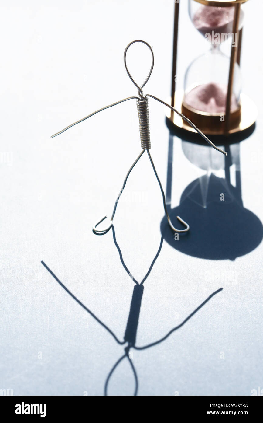 Man made from aluminum wire standing against hourglass Stock Photo - Alamy