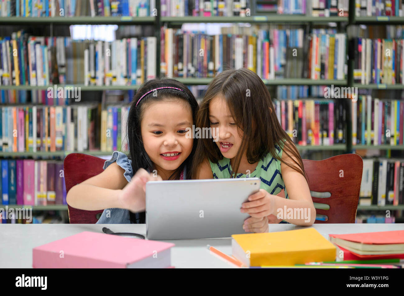Two little happy cute girls playing on a tablet PC computing device in ...