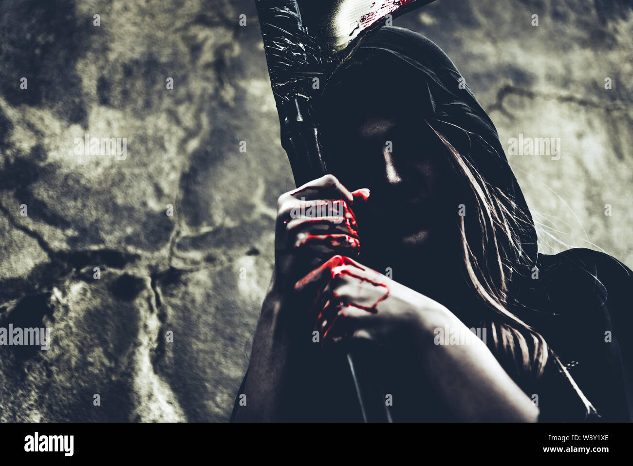Demon witch with reaper standing in front of grunge wall background ...