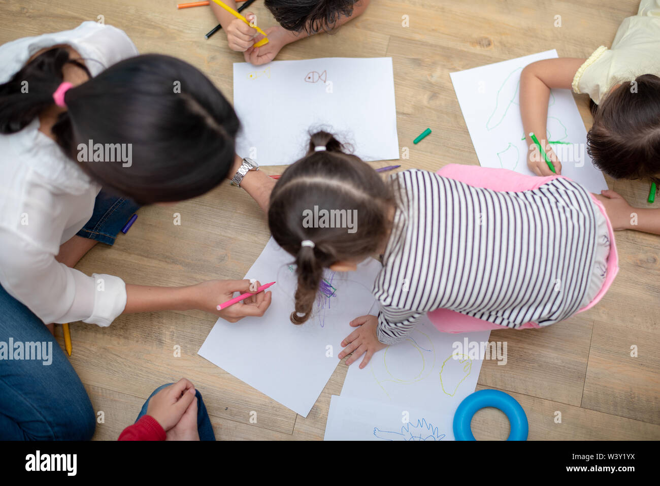 Group of preschool student and teacher drawing on paper in art class ...