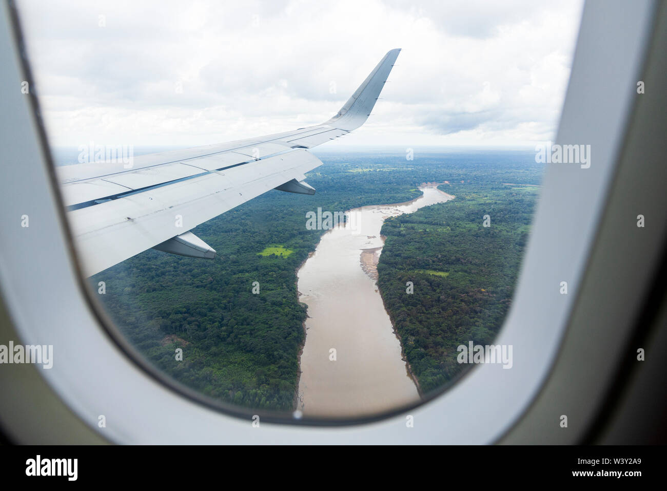 Aerial view from inside a passenger plane over a river in the Amazonia ...