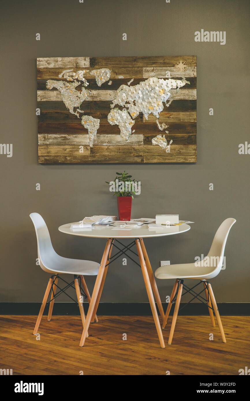 Vertical shot of two chairs and a table near a grey wall with a wooden ...