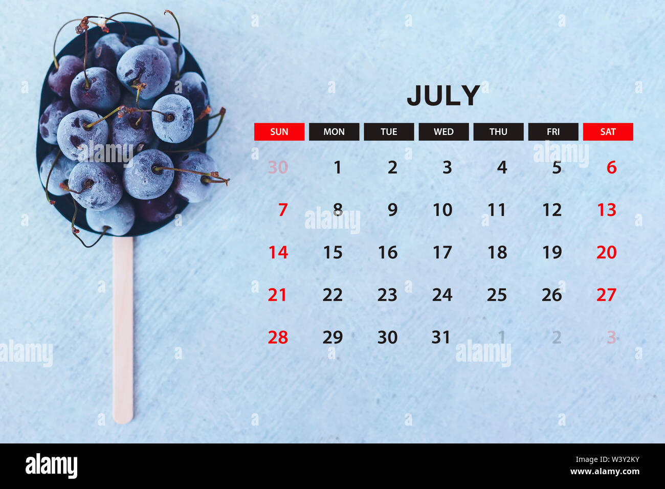 July calendar. Stack of frozen sweet cherries with July month calendar ...