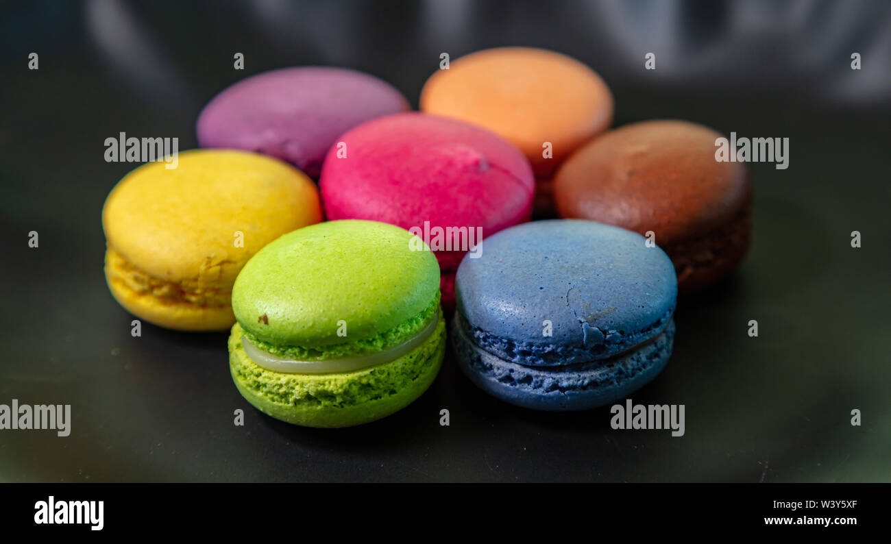 Macarons pastel colors with chocolate cream on black background, close ...