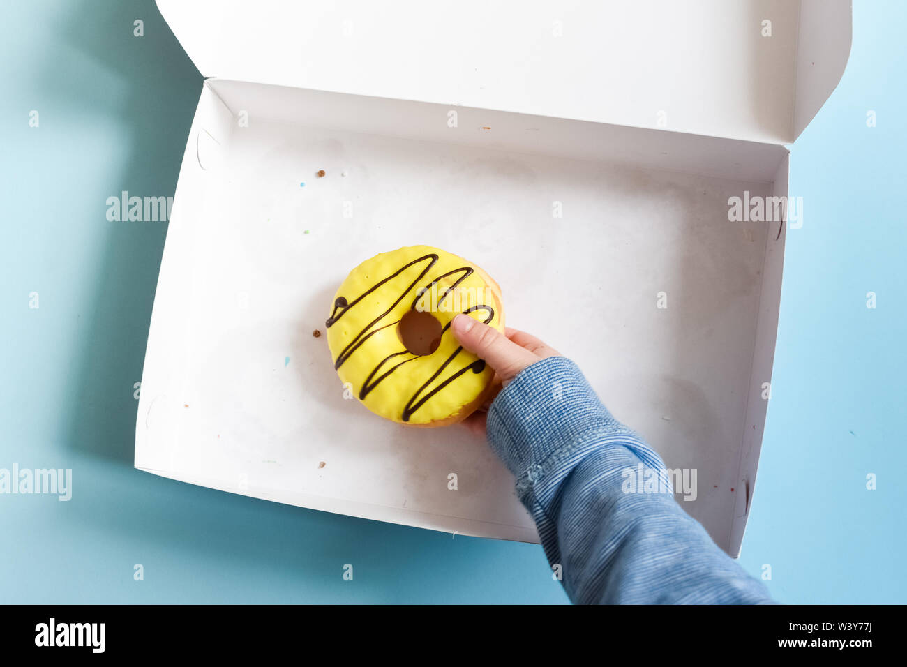 Donut box with a young male child's hand reaching to grab the last ...