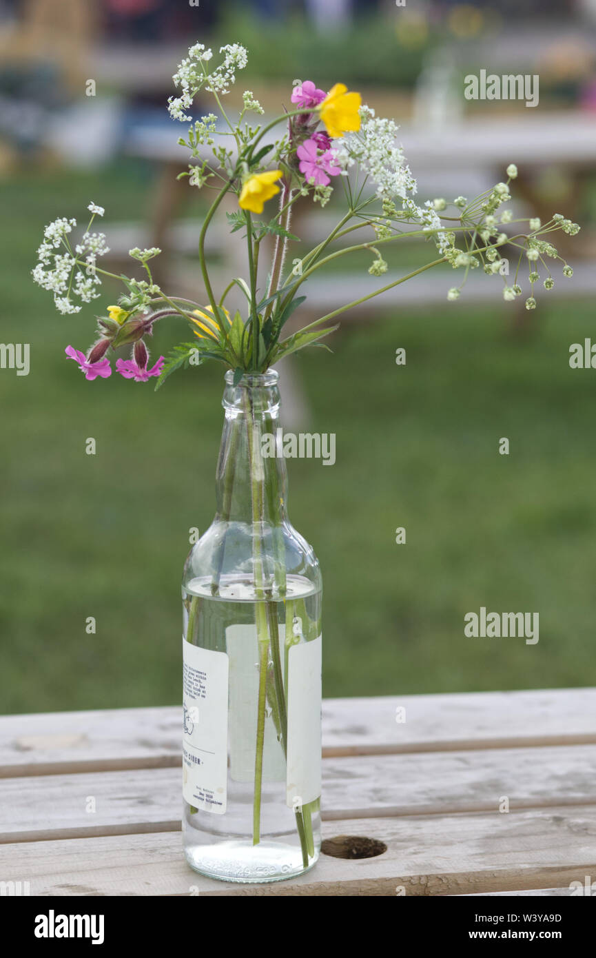 wild cut flowers in a wine bottle table decoration Stock Photo - Alamy
