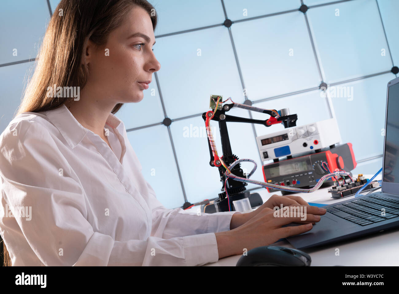A young woman writes an algorithm for the robot arm. Science Research ...