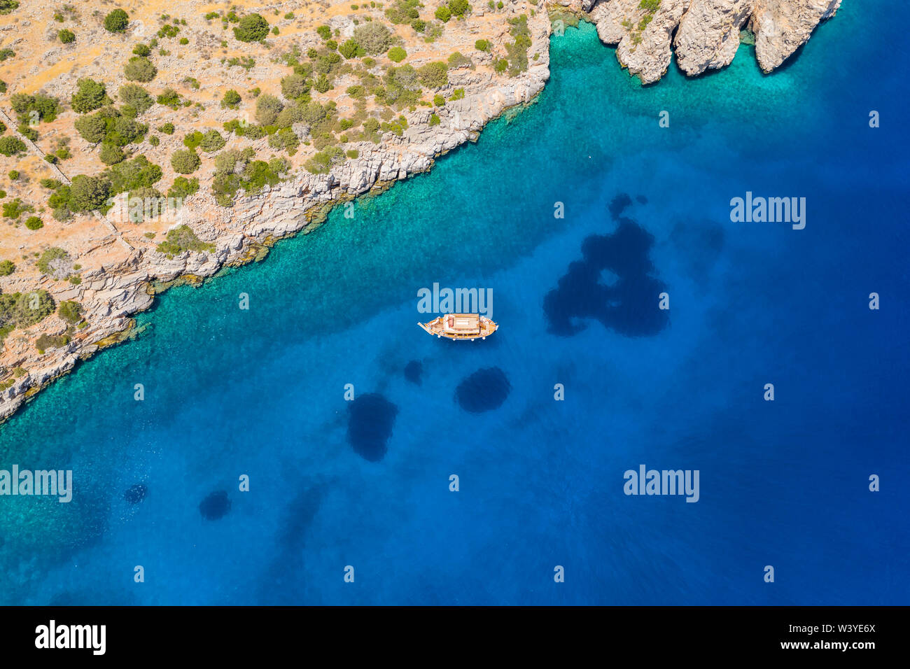 Aerial drone view of a traditional wooden boat on a crystal clear blue ...