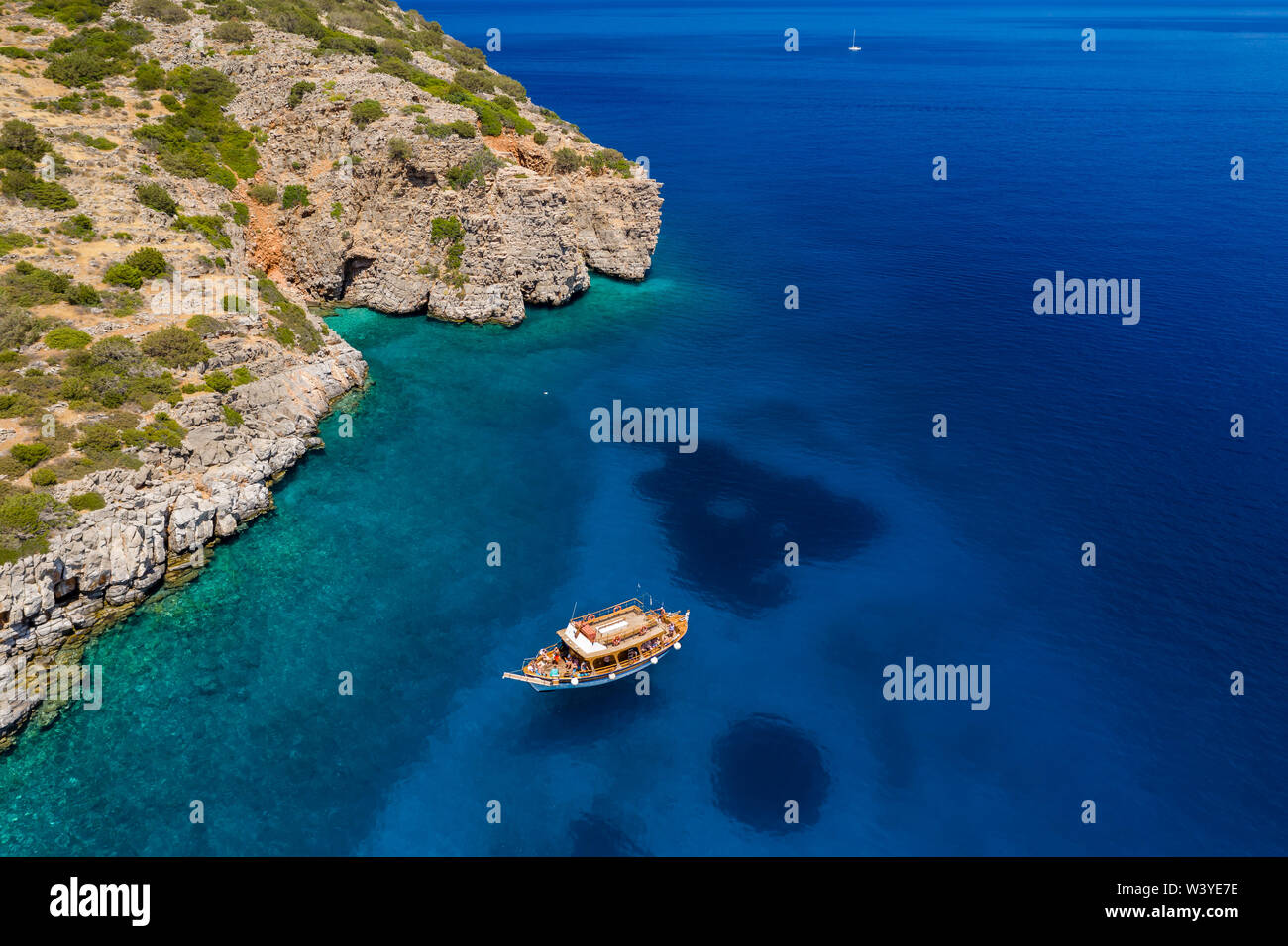 Aerial drone view of a traditional wooden boat on a crystal clear blue ...