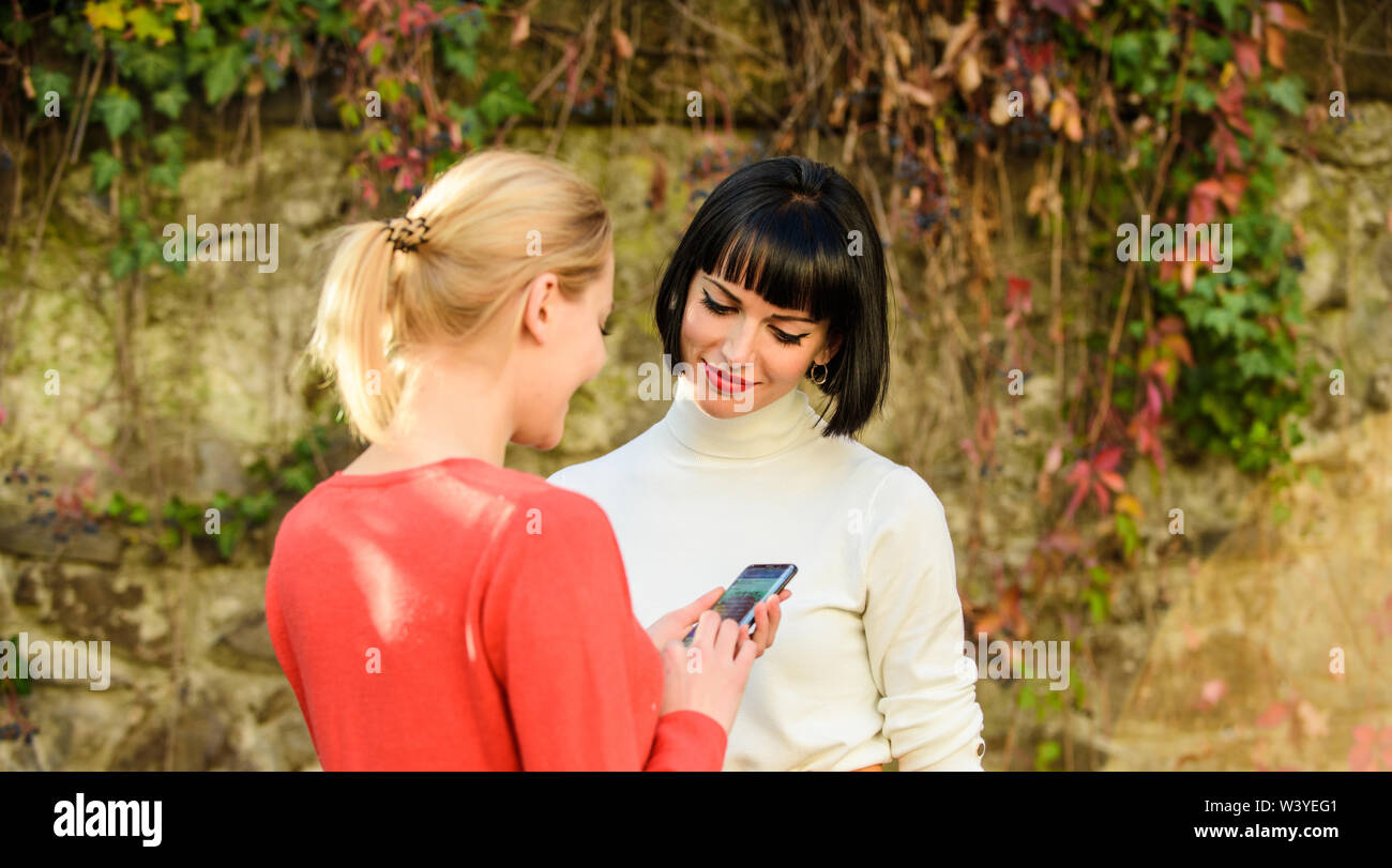 Sharing link. Two women with smartphone communicating outdoors. Social ...