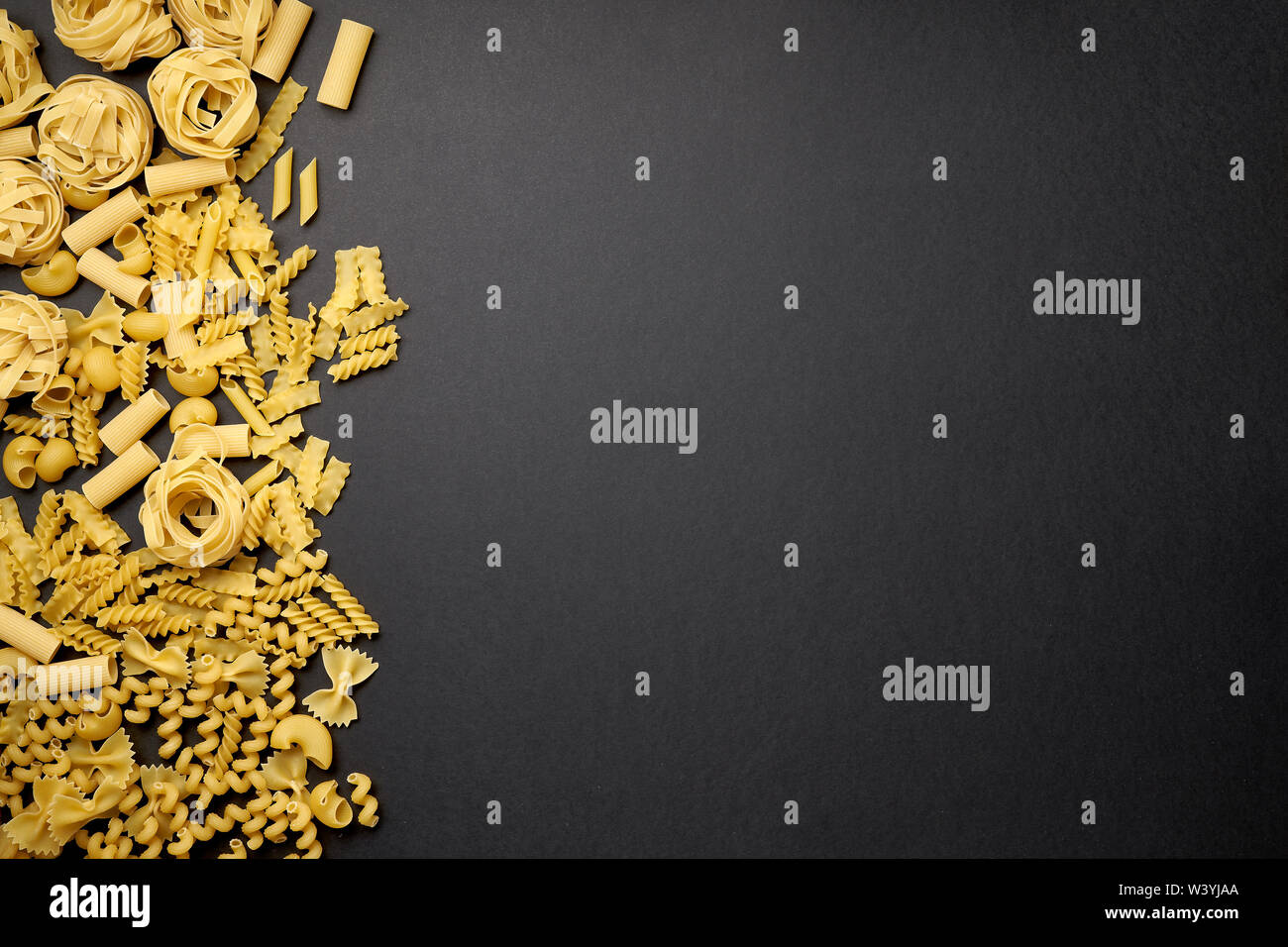 Assorted types of pasta on black background. Top view. Various forms of ...