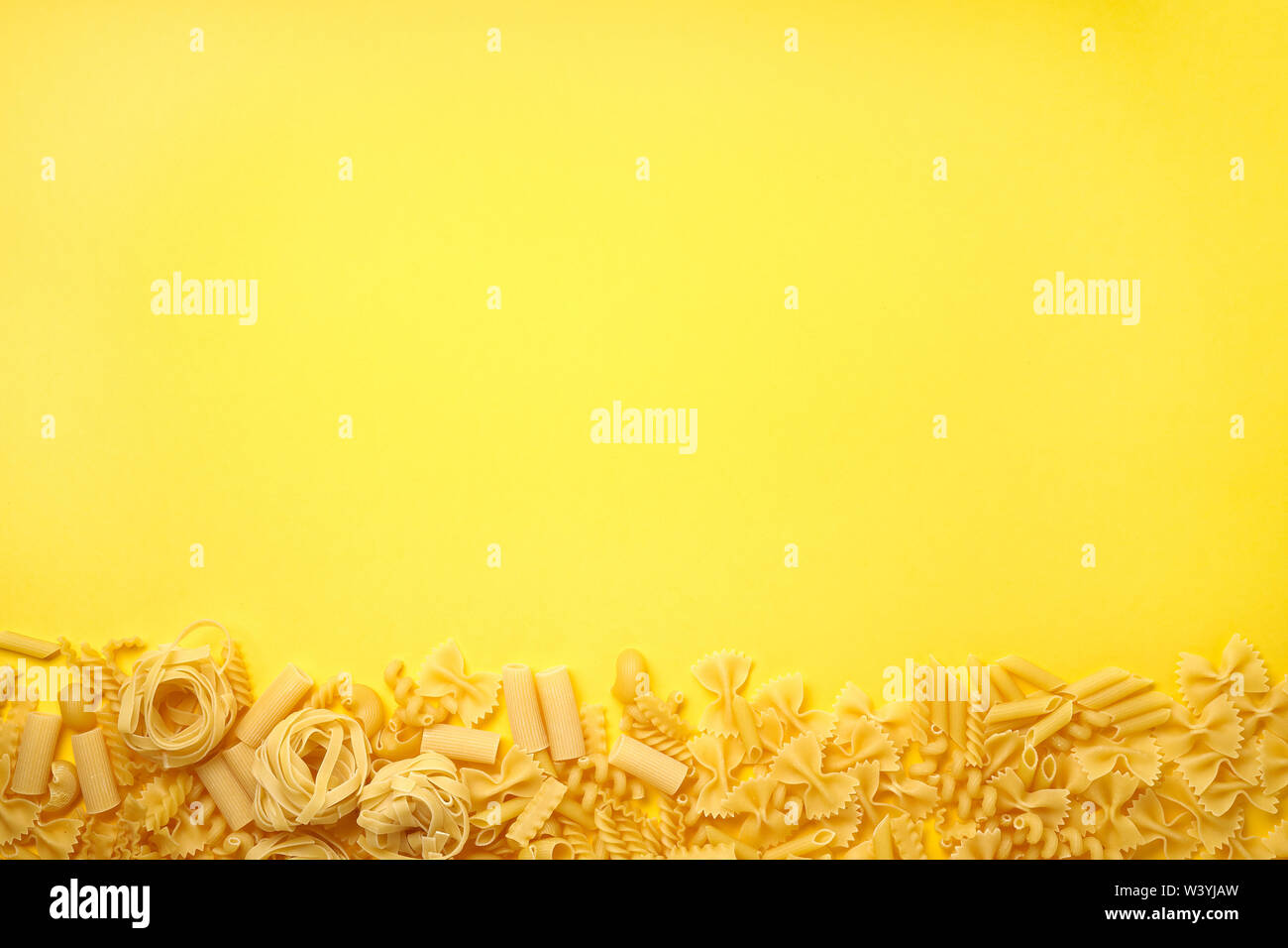 Assorted types of pasta on yellow background. Top view. Various forms ...
