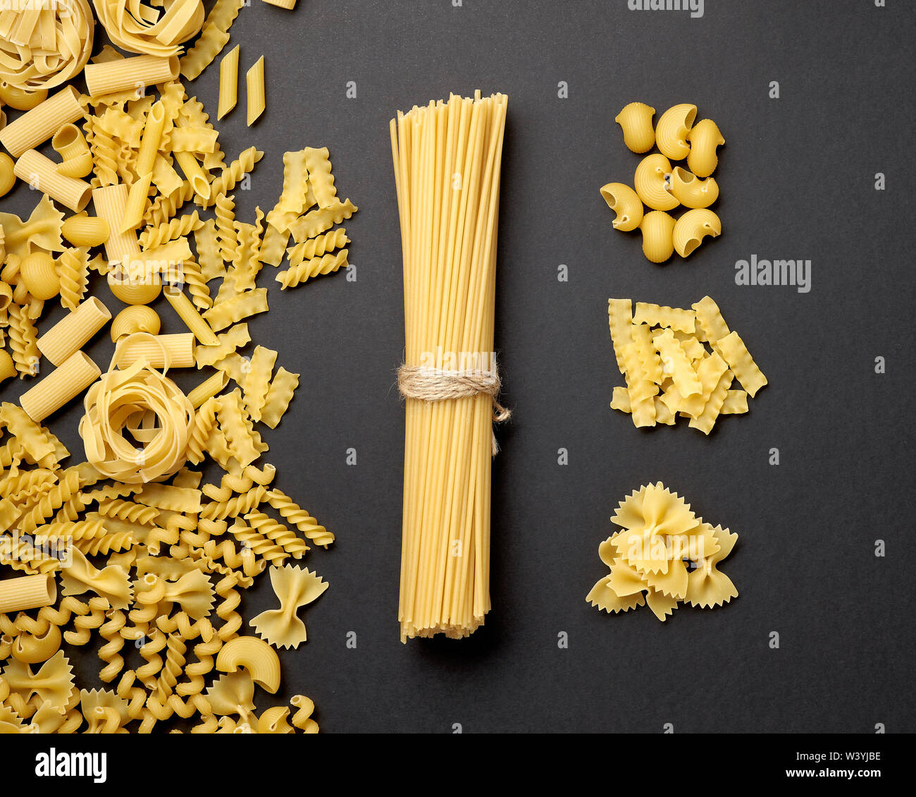 Assorted types of pasta on black background. Top view. Various forms of ...