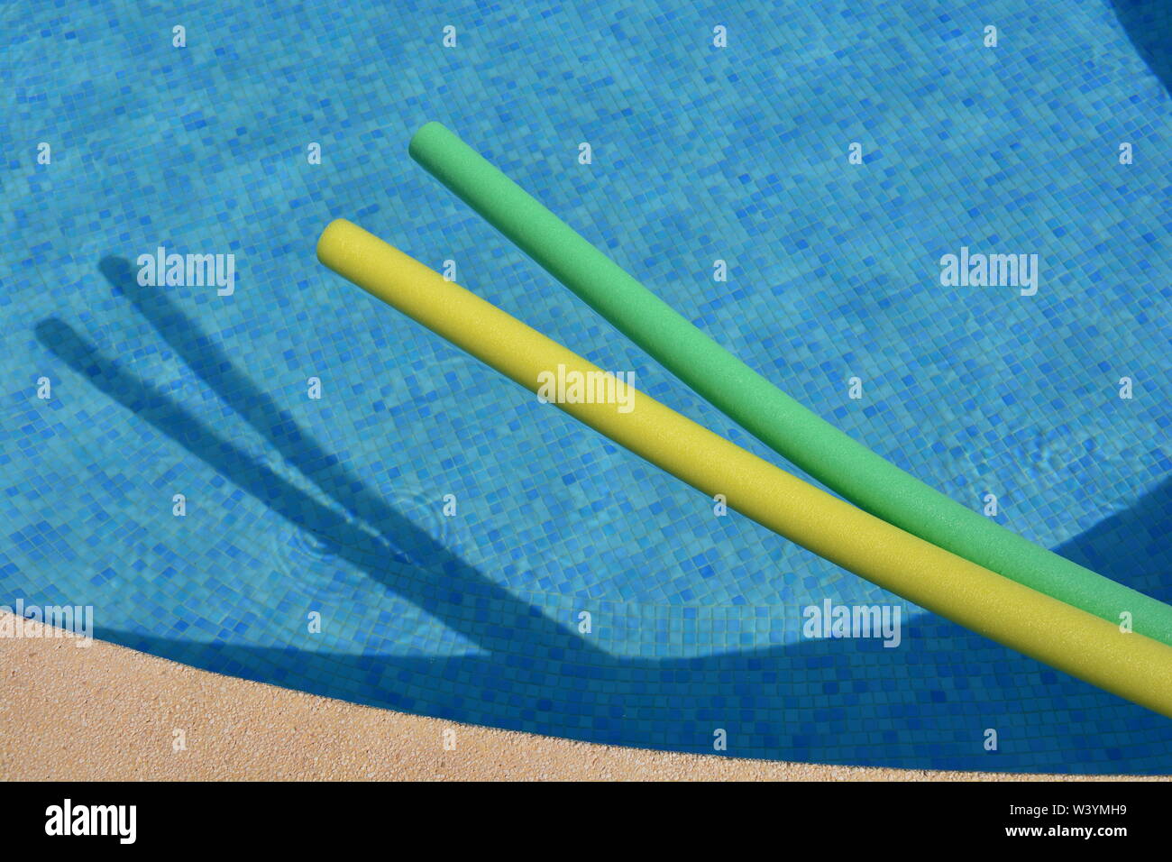 Colorful pool noodles floating in a swimming pool, close up. Creative ...