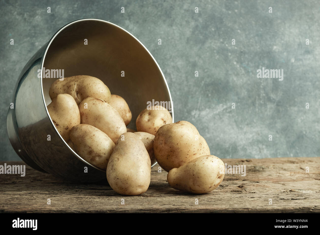 Fresh potato in silver bowl on a old oak wooden table and beautiful ...