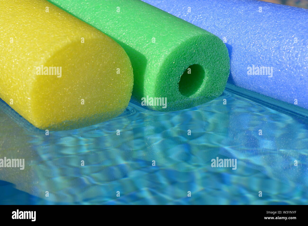 Colorful pool noodles floating in a swimming pool, close up. Creative ...
