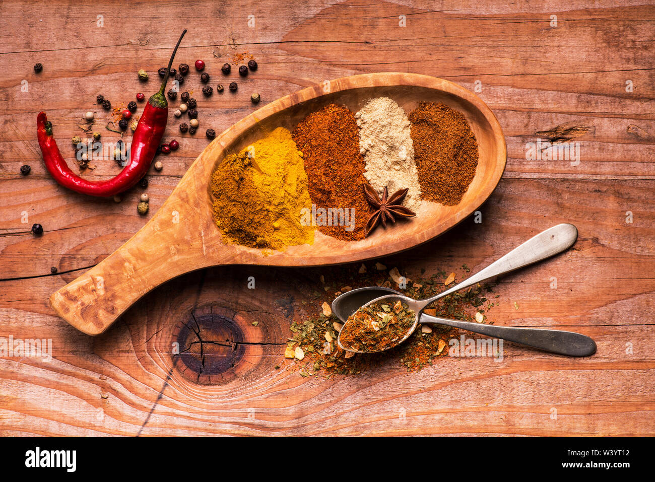 assortment of brightly colored spices in wooden bowl on rough ...