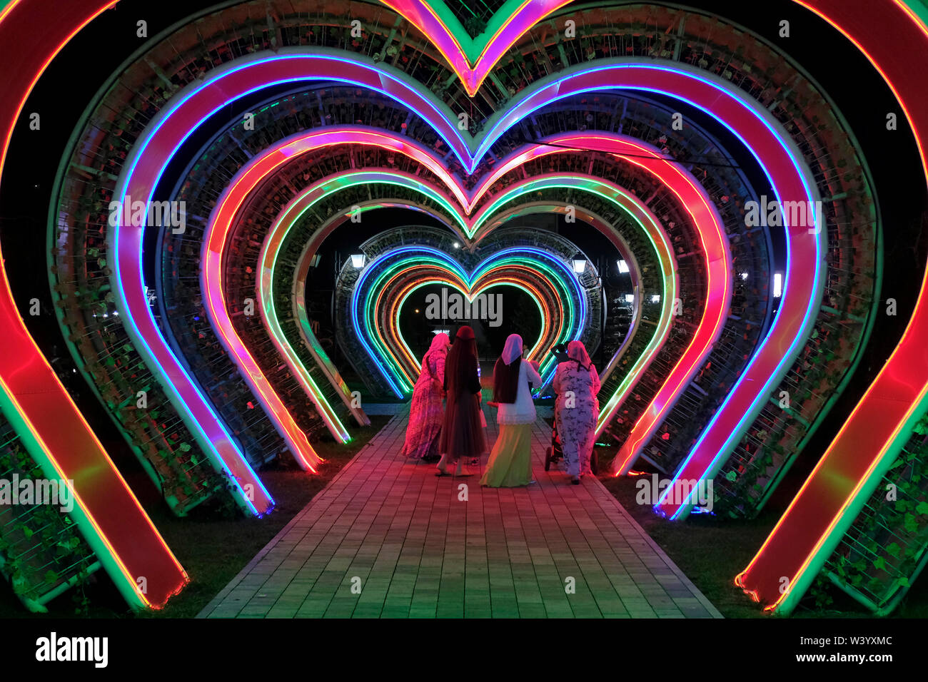 Chechen women walk at night through an illuminated heart-shaped tunnel ...