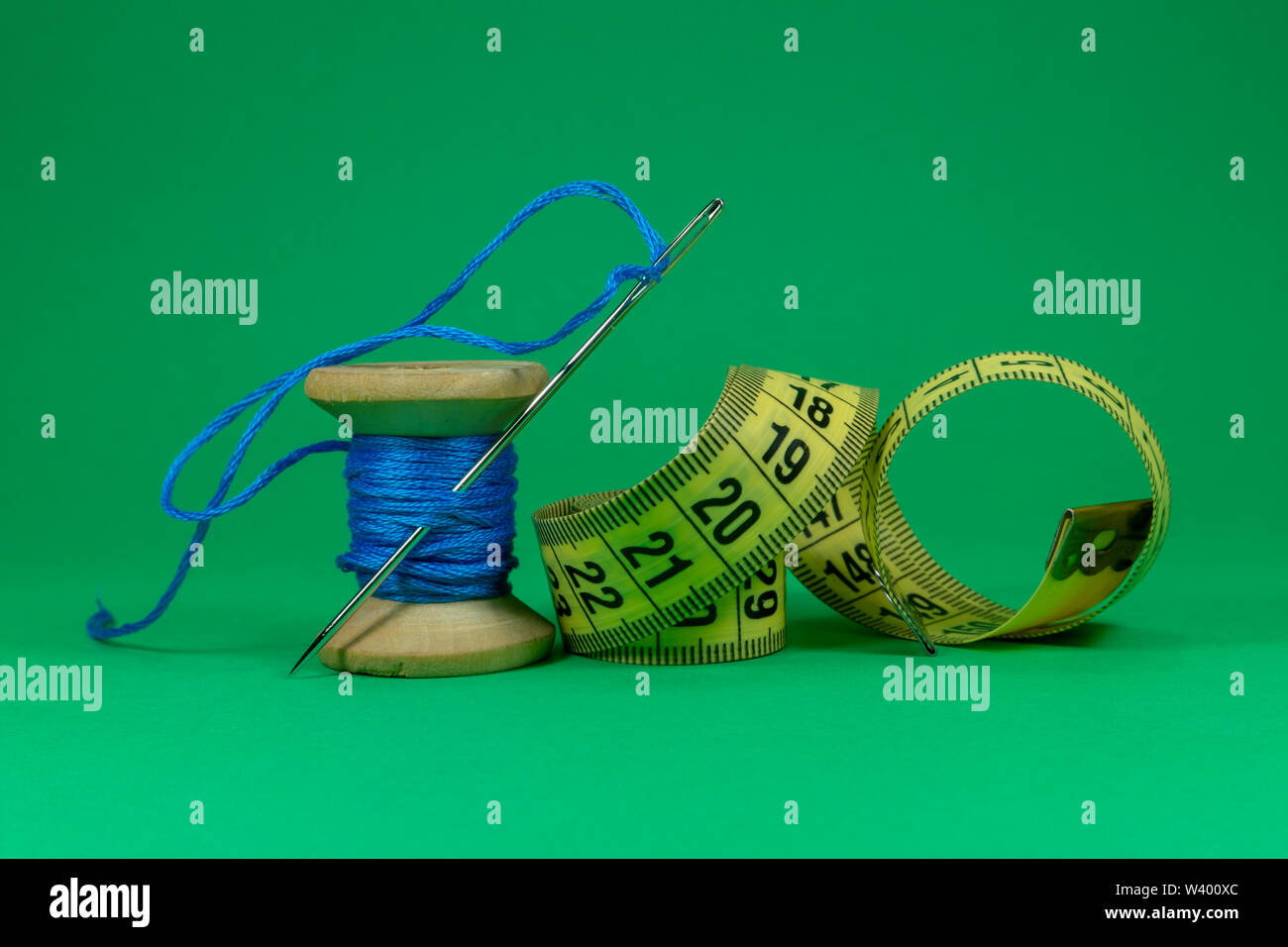 A close up image of a tape measure, spool of blue thread and sewing ...