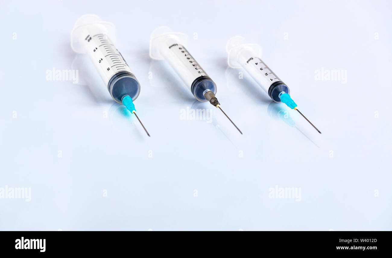 Three syringes of different capacity on a white table, prepared for ...