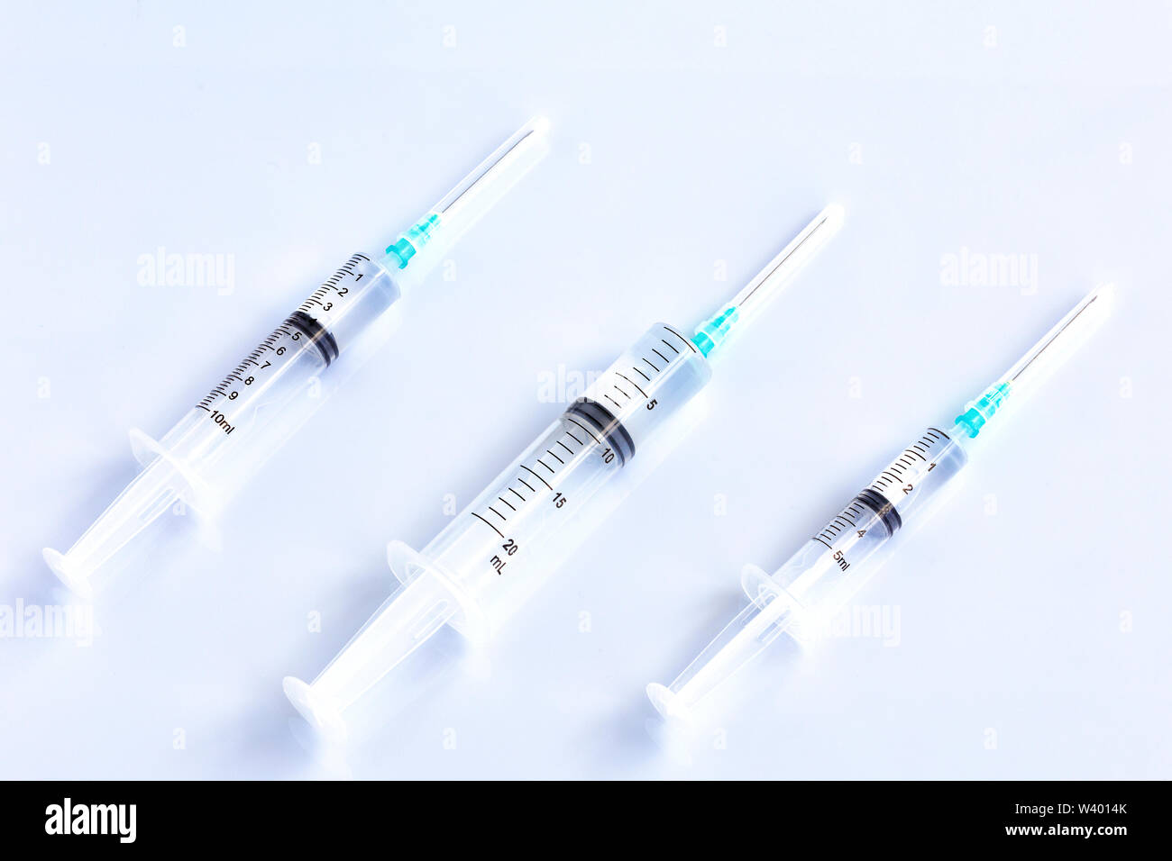 Three syringes of different capacity on a white table, prepared for ...