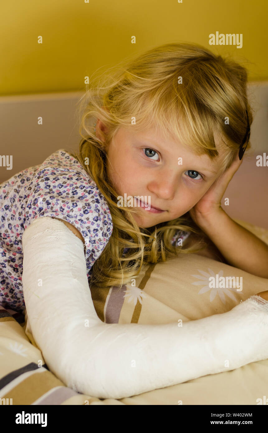 hurt blond girl with broken hand lying on hand Stock Photo - Alamy