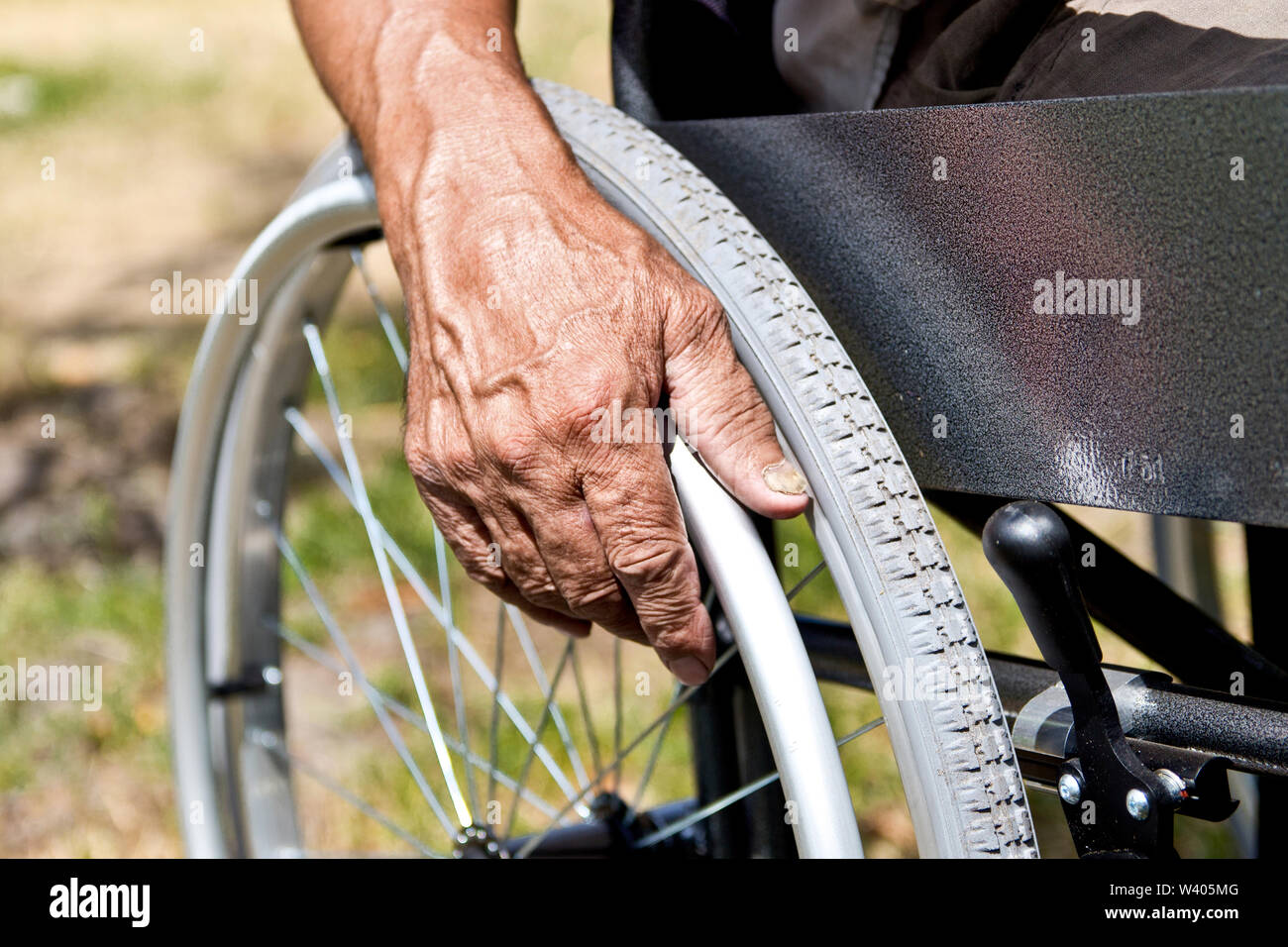 A disabled man is sitting in a wheelchair ,Holds his hands on the wheel ...