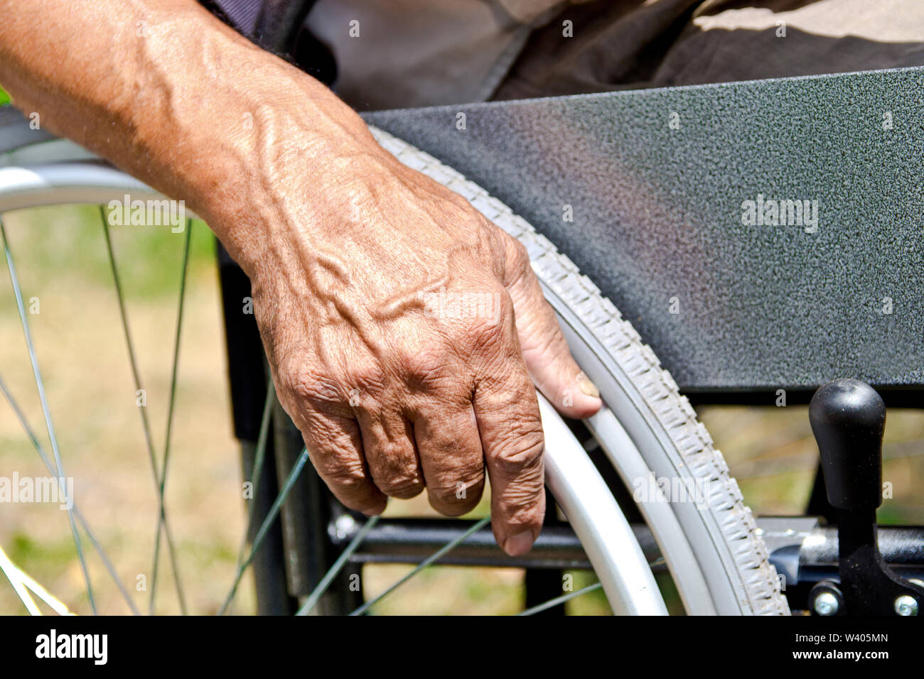 A disabled man is sitting in a wheelchair ,Holds his hands on the wheel ...