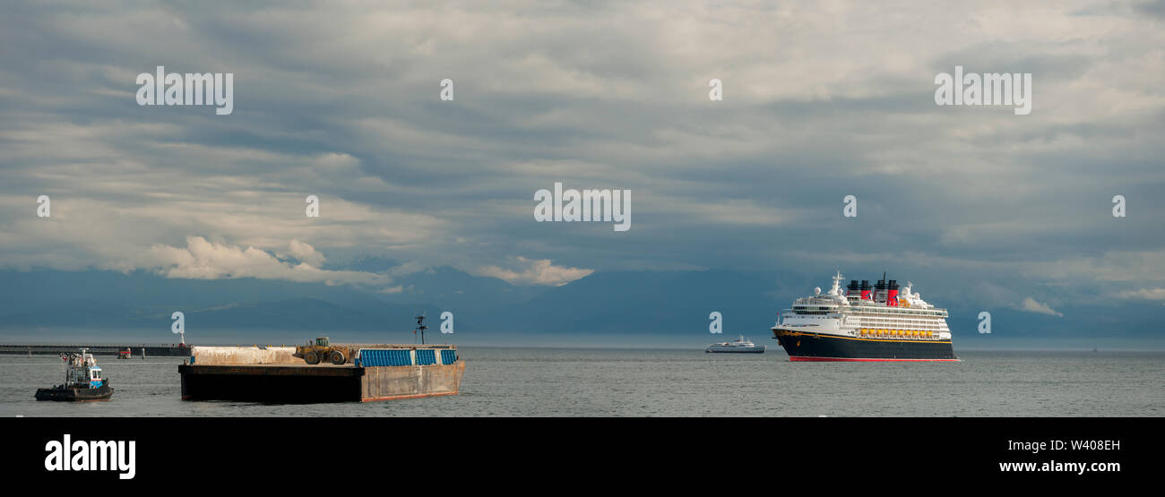Luxury cruise ship Disney Wonder departing port of Victoria with barge ...