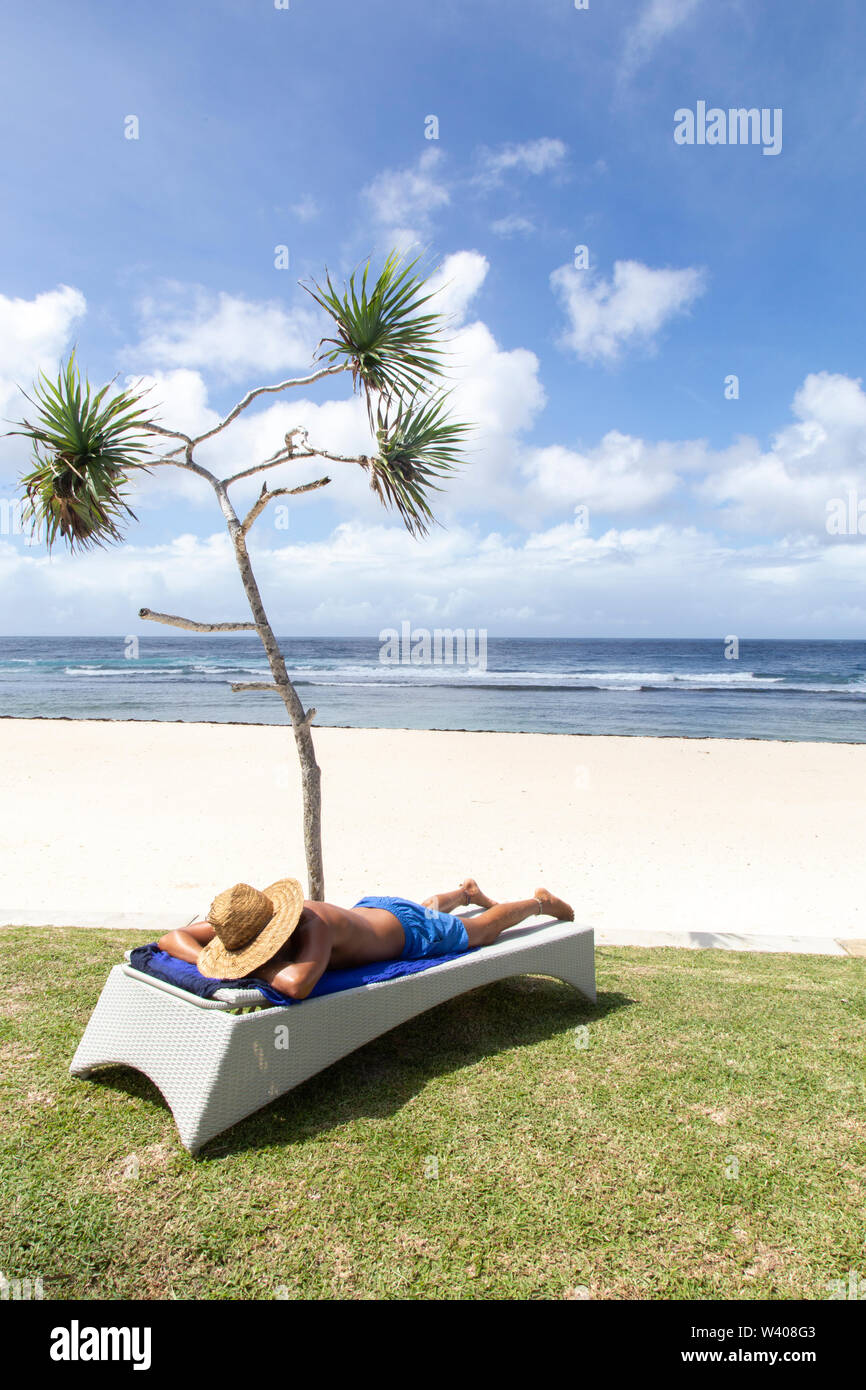 One man, wearing blue bathingsuits, tanning on beach chair, Vanuatu ...