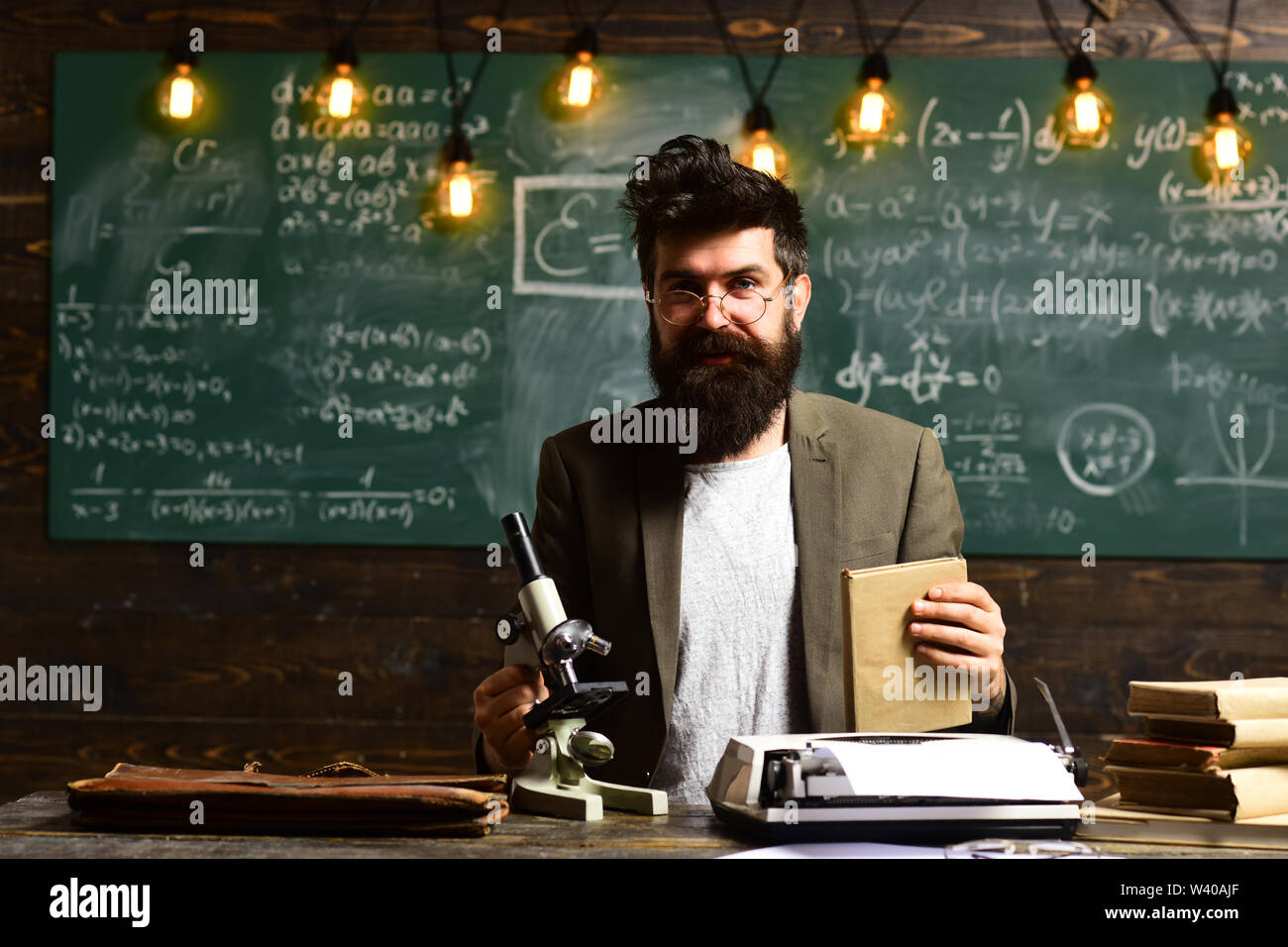 Bearded man with book and retro typewriter. Scientist make research ...