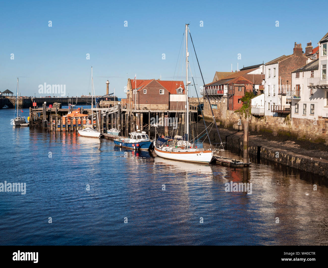 The harbour at Whitby with the buildings by the quayside and boats ...