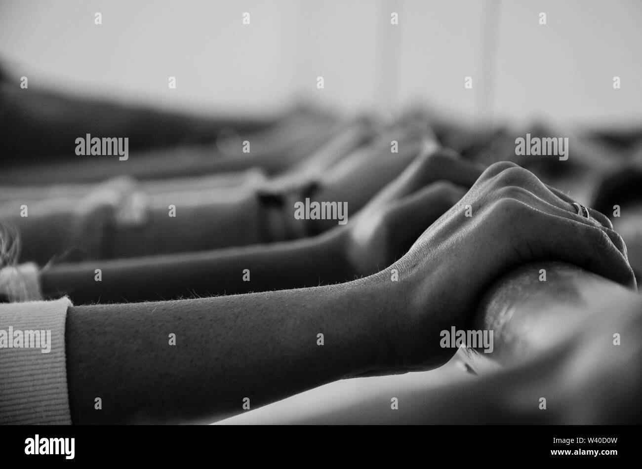 Children’s hands grip a railing for balance as they preform a yoga pose ...