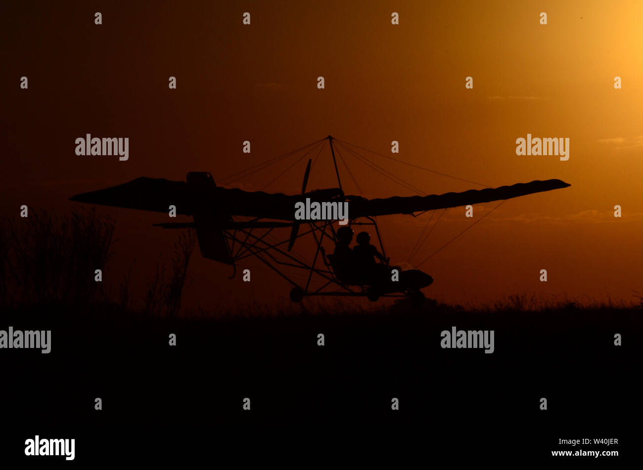 Ultralight airplane at sunset. Two people flying low with tranquility ...