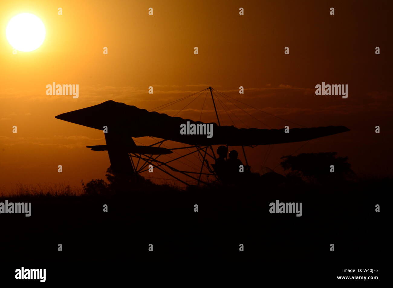 Ultralight airplane at sunset. Two people flying low with tranquility ...