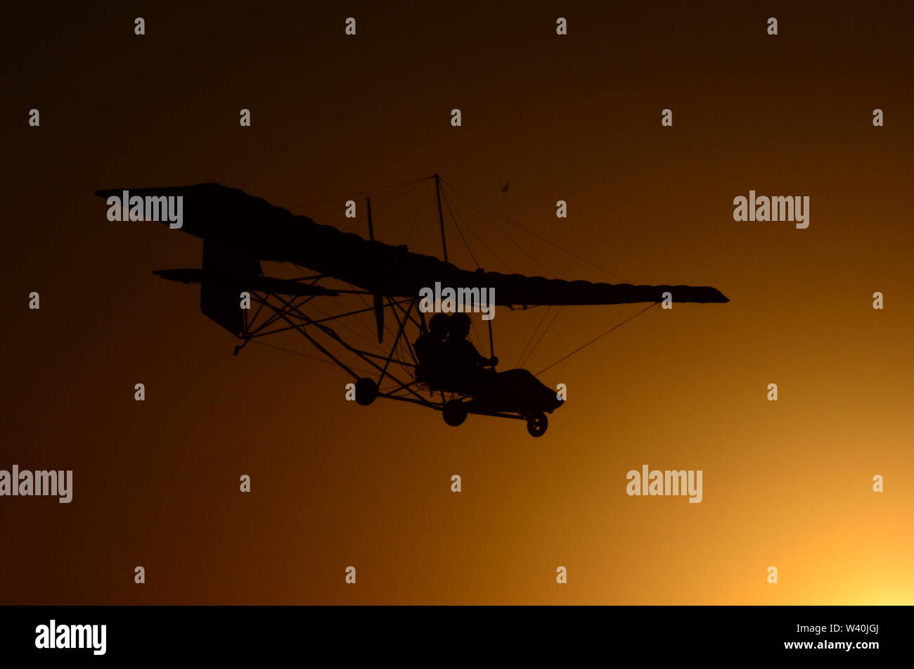 Ultralight airplane at sunset. Two people flying low with tranquility ...