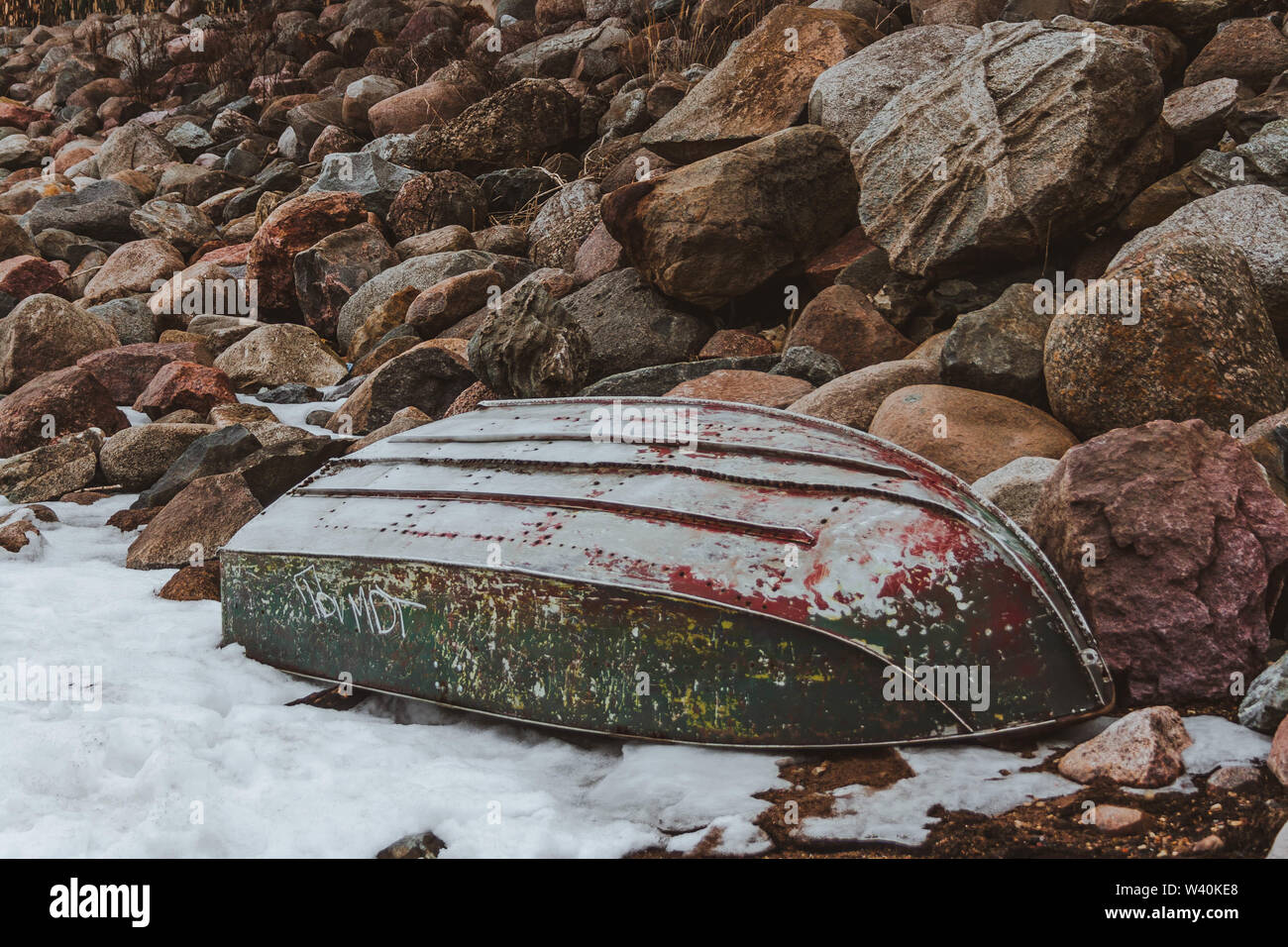 Overturned boat resting on a rocks in wintertime Stock Photo - Alamy