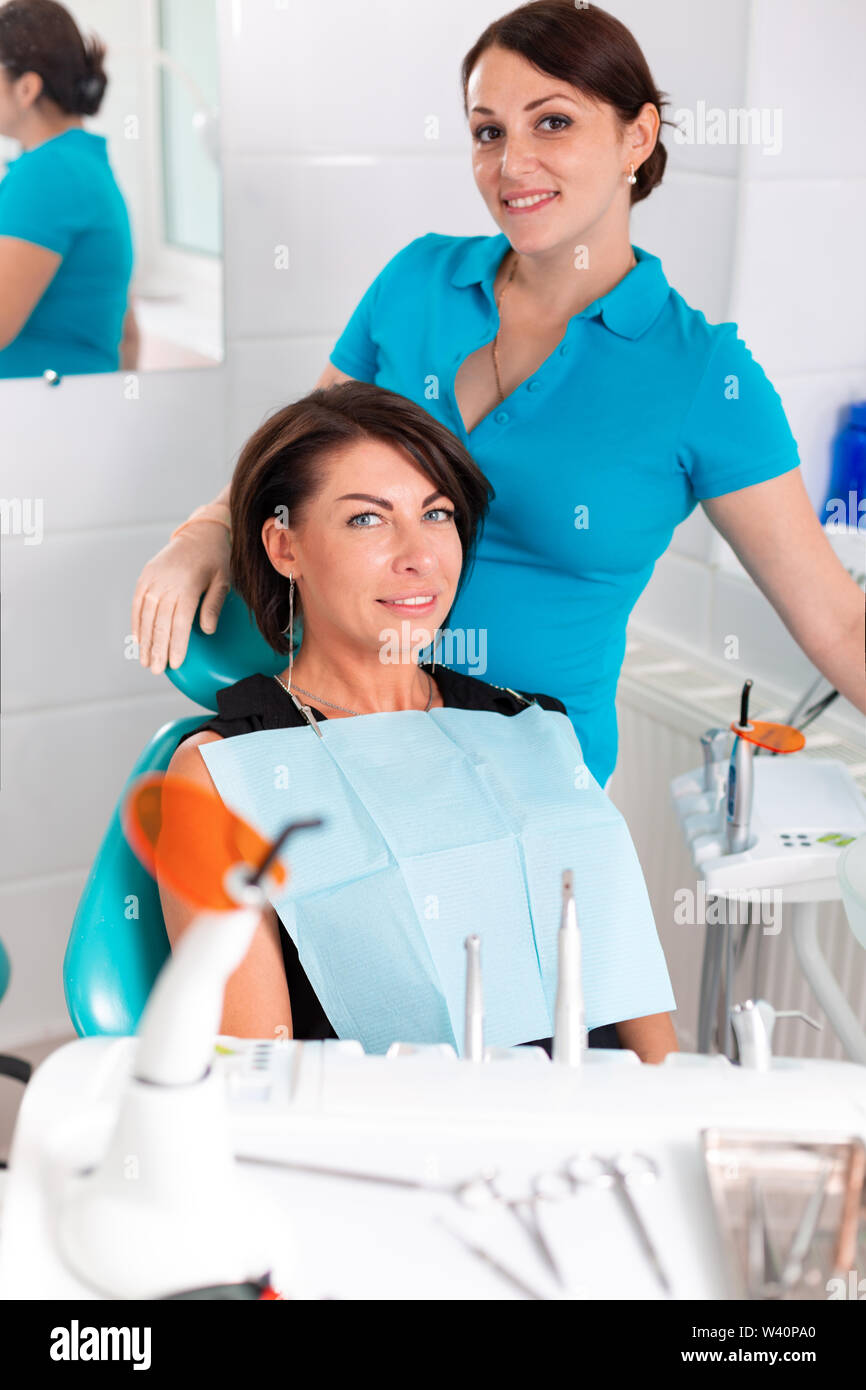 The dentist and her happy patient look at the camera and smile ...