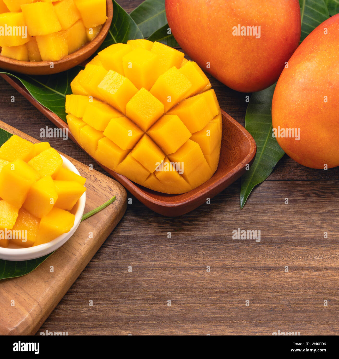 Fresh chopped mango cubes on wooden cutting board and rustic timber ...
